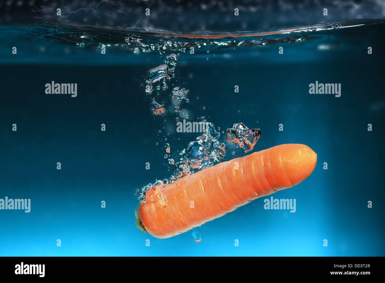 Carrot in the water splash over blue background. Healthy food and ...