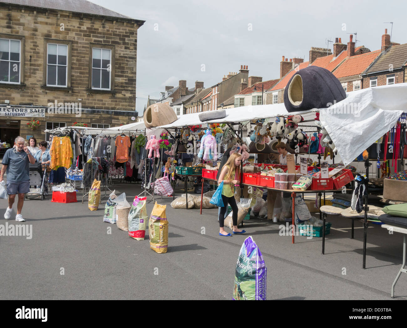 Shoppers buying clothing and pet food from stalls in the weekly street ...