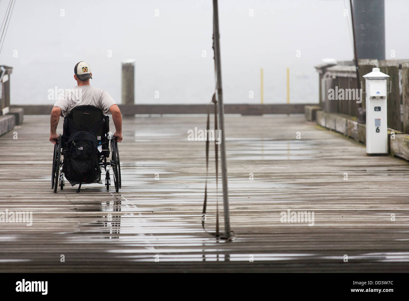 A disabled sailor wheels himself along the dock going to his boat to ...