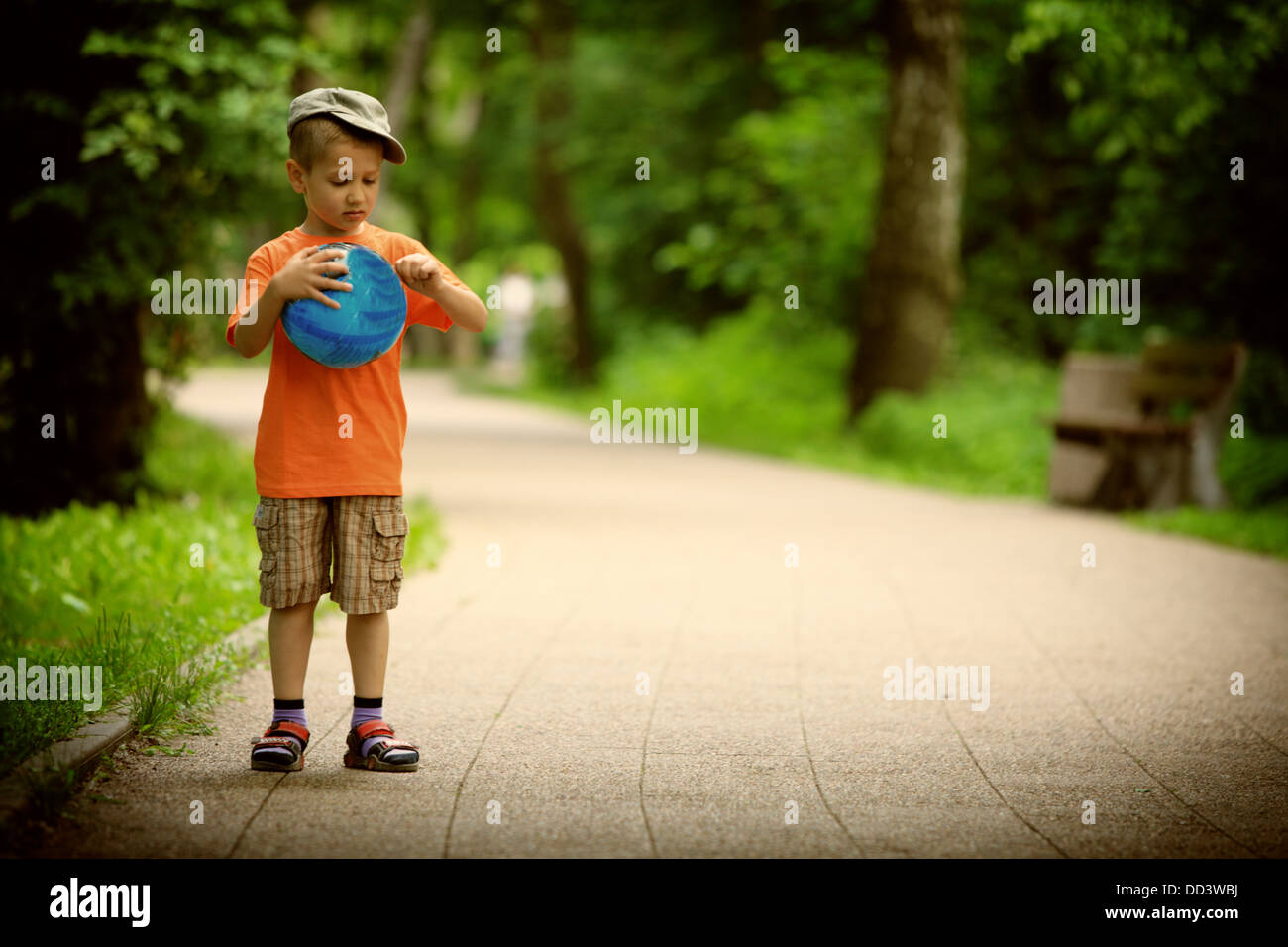 Boy in action young kid playing with ball in park outdoors. Healthy ...