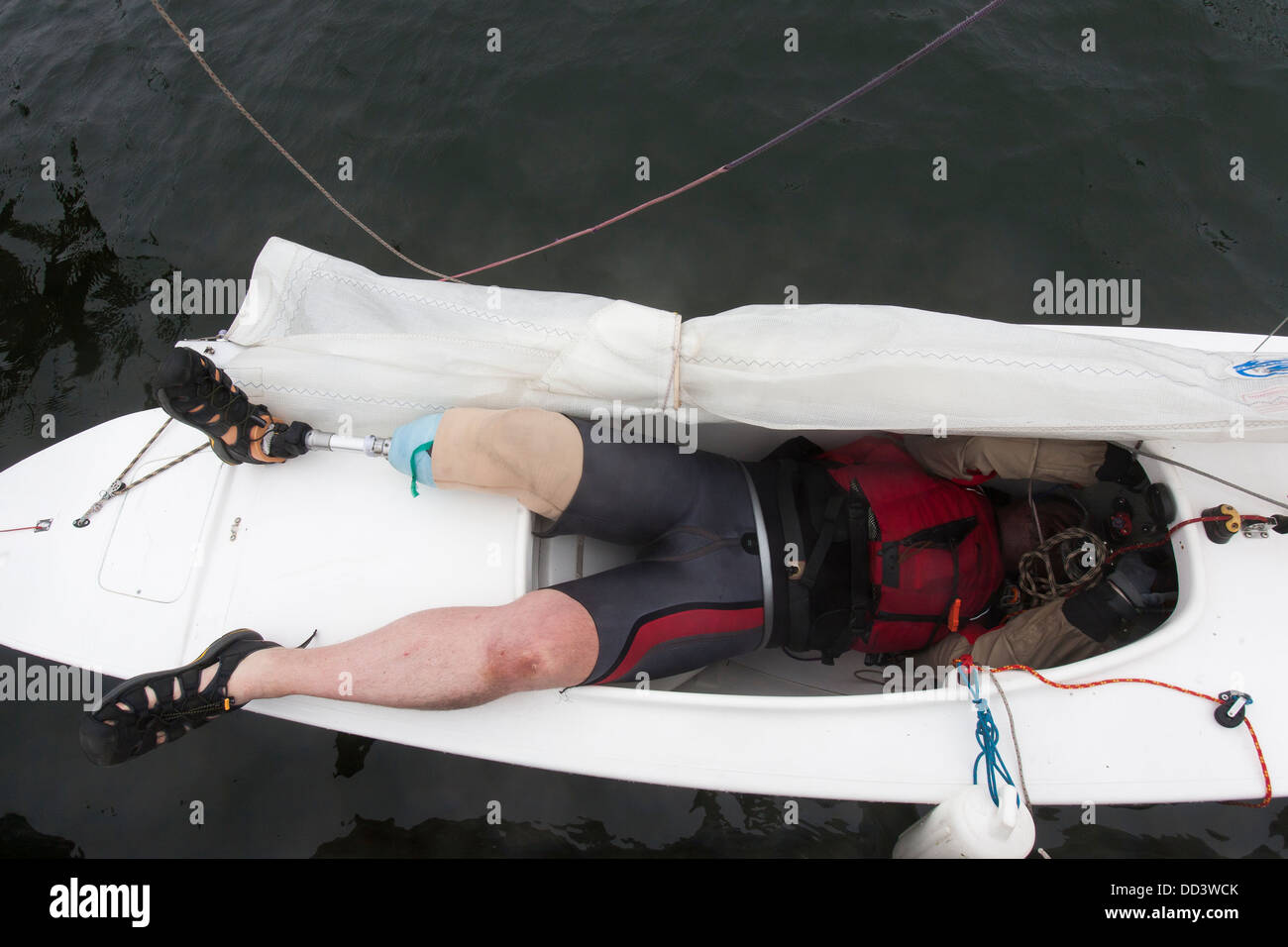 An amputee sailor lies upside down in his 2.4 meter sailboat to fix the ...