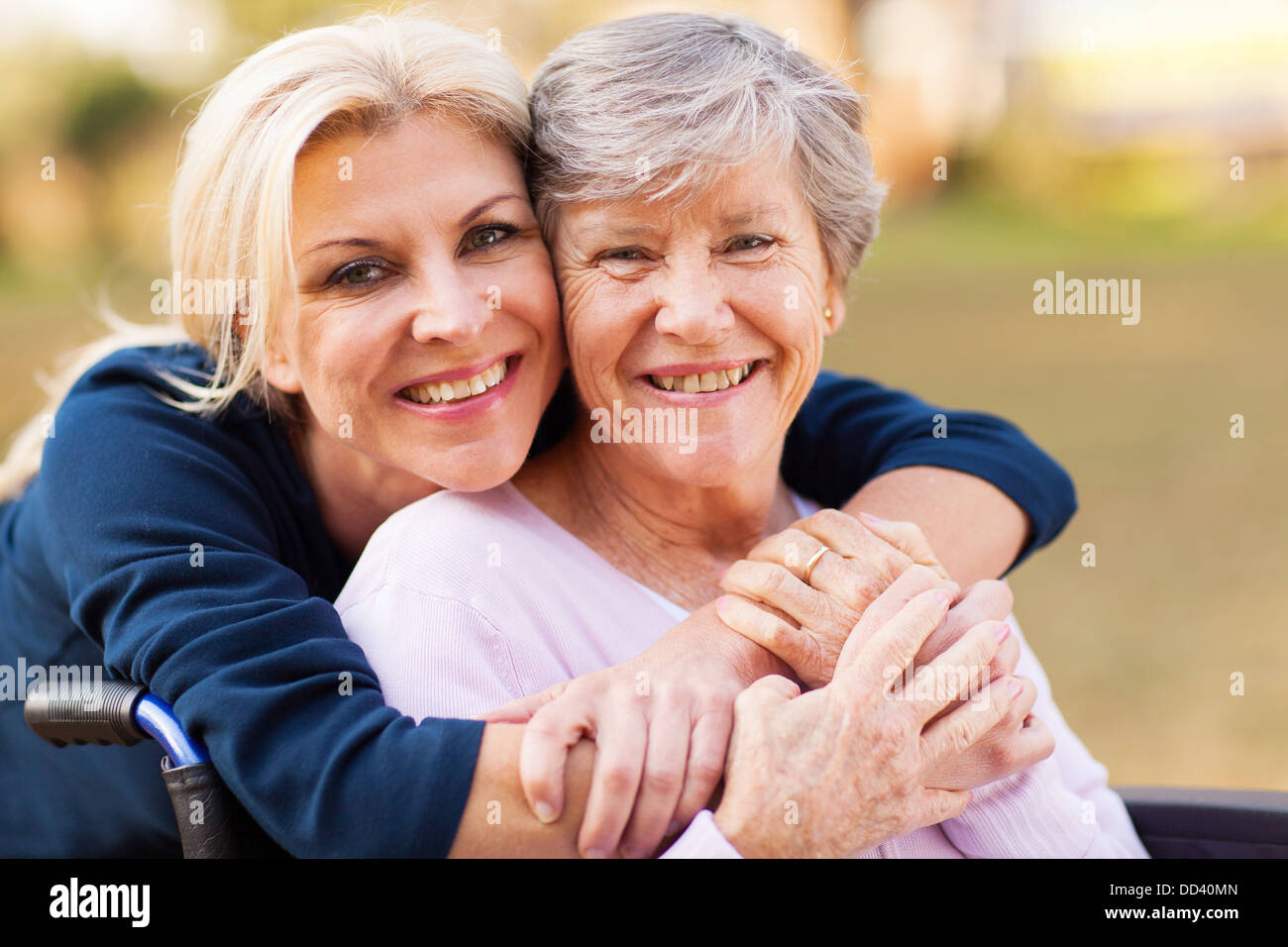 cheerful middle aged woman embracing disabled senior mother outdoors ...