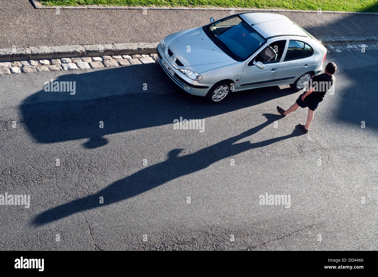 Long shadow of casually dressed man walking to parked car - France ...