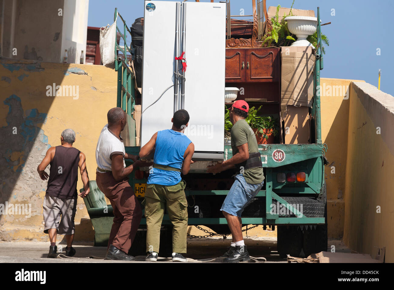 Men load a fridge and other contents of an apartment into the back of ...