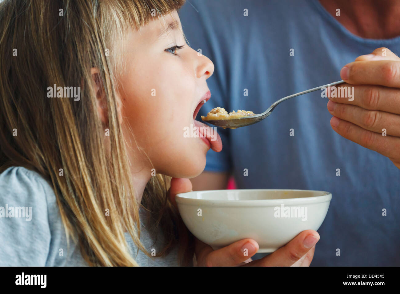 Child Being Spoon Fed Food From A Bowl By Her Father; Spain Stock Photo ...