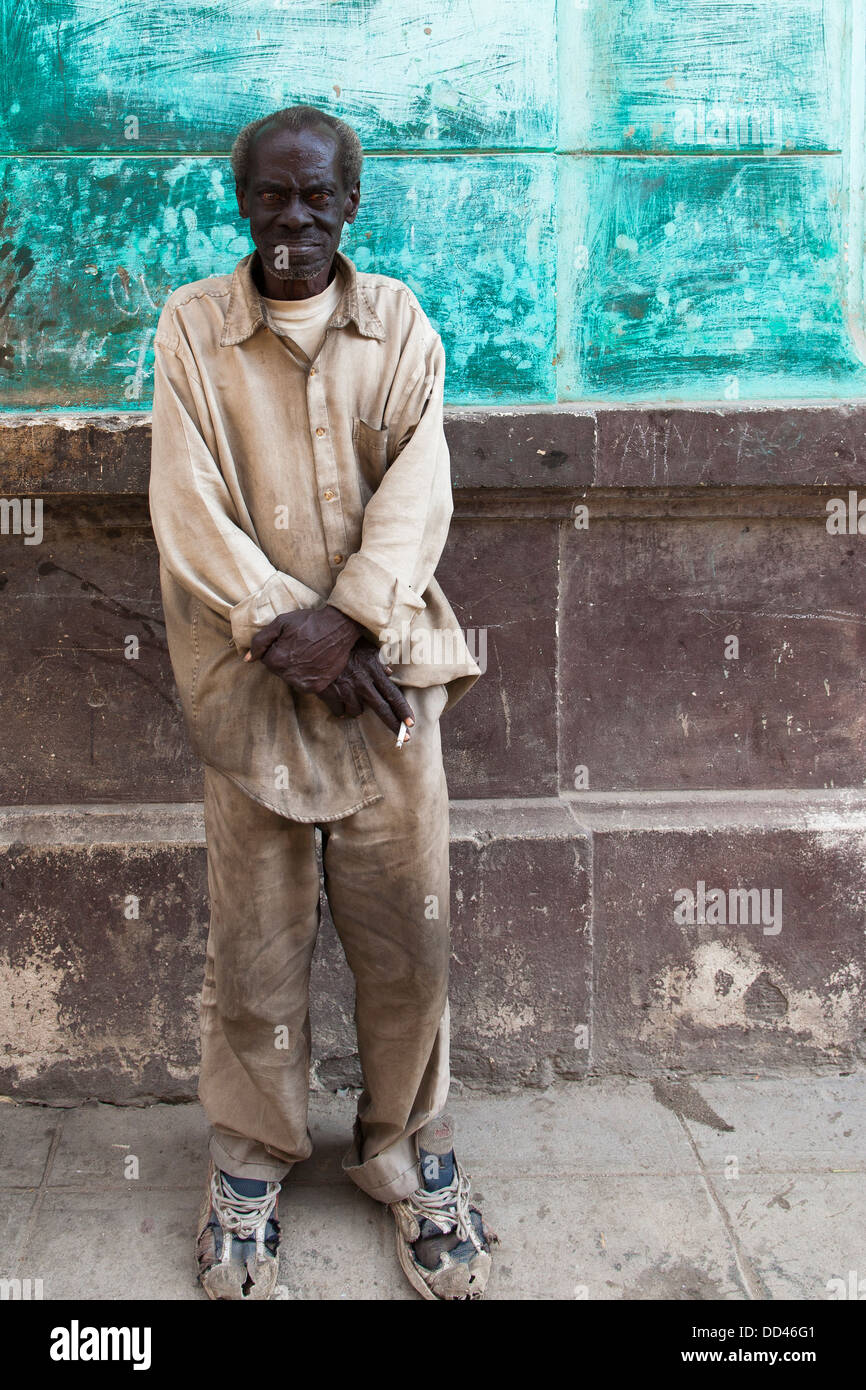 An impoversihed Cuban man stands next to a colorful wall in Havana ...