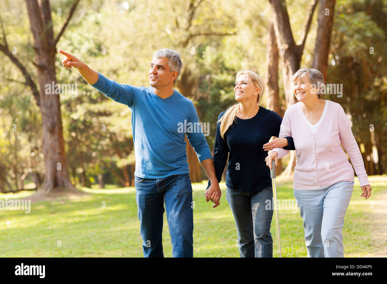 cheerful middle aged couple taking elderly mother for a walk in forest ...