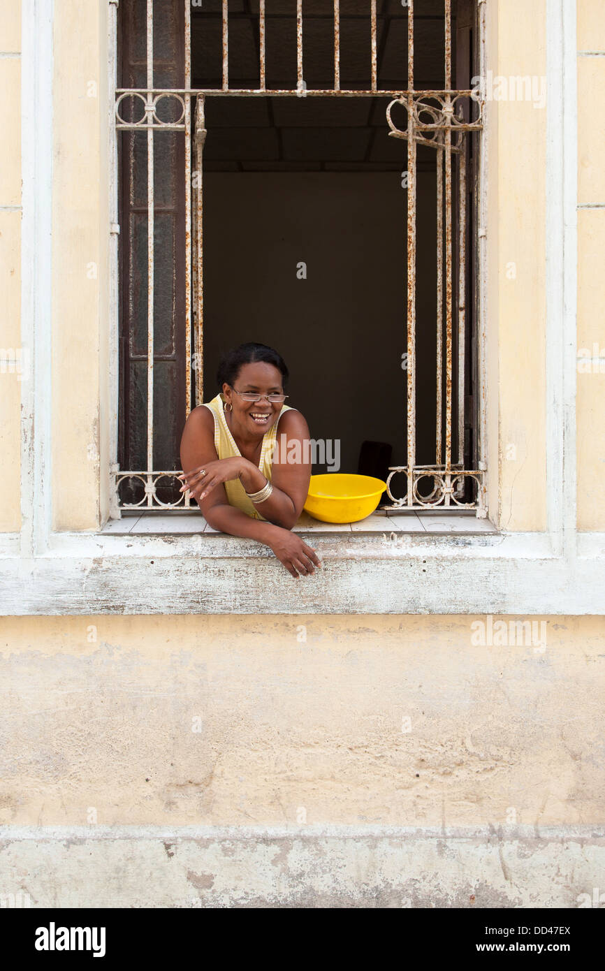 A Cuban Lady smiles and laughs while leaning out from a window in ...