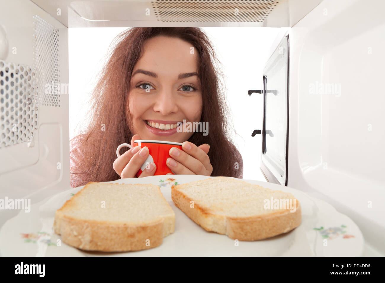 Smiling girl looks in a microwave Stock Photo - Alamy