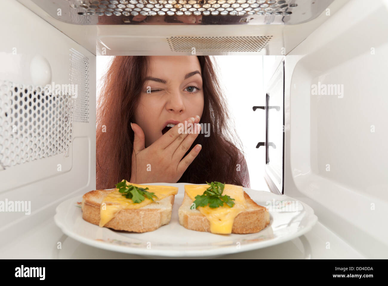 Girl looks in a microwave and yawn Stock Photo - Alamy