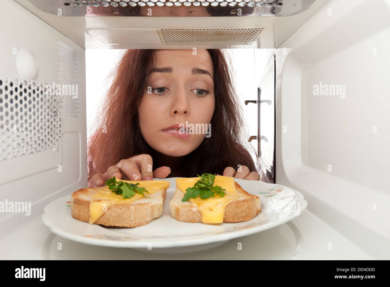 Attractive girl looks in a microwave Stock Photo - Alamy
