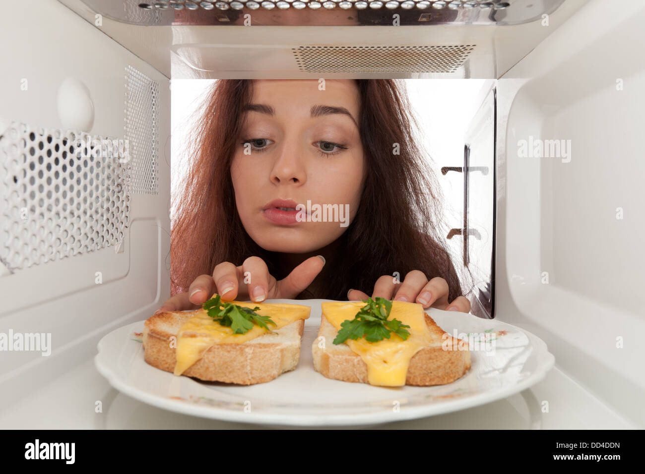Attractive girl looks in a microwave Stock Photo - Alamy