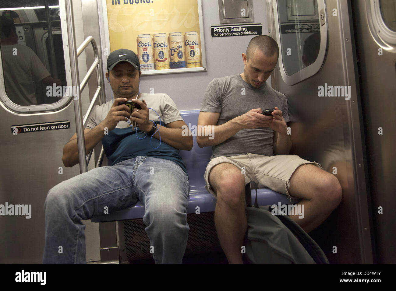 Two men use their electronic devices as they ride the NY City Subway in ...