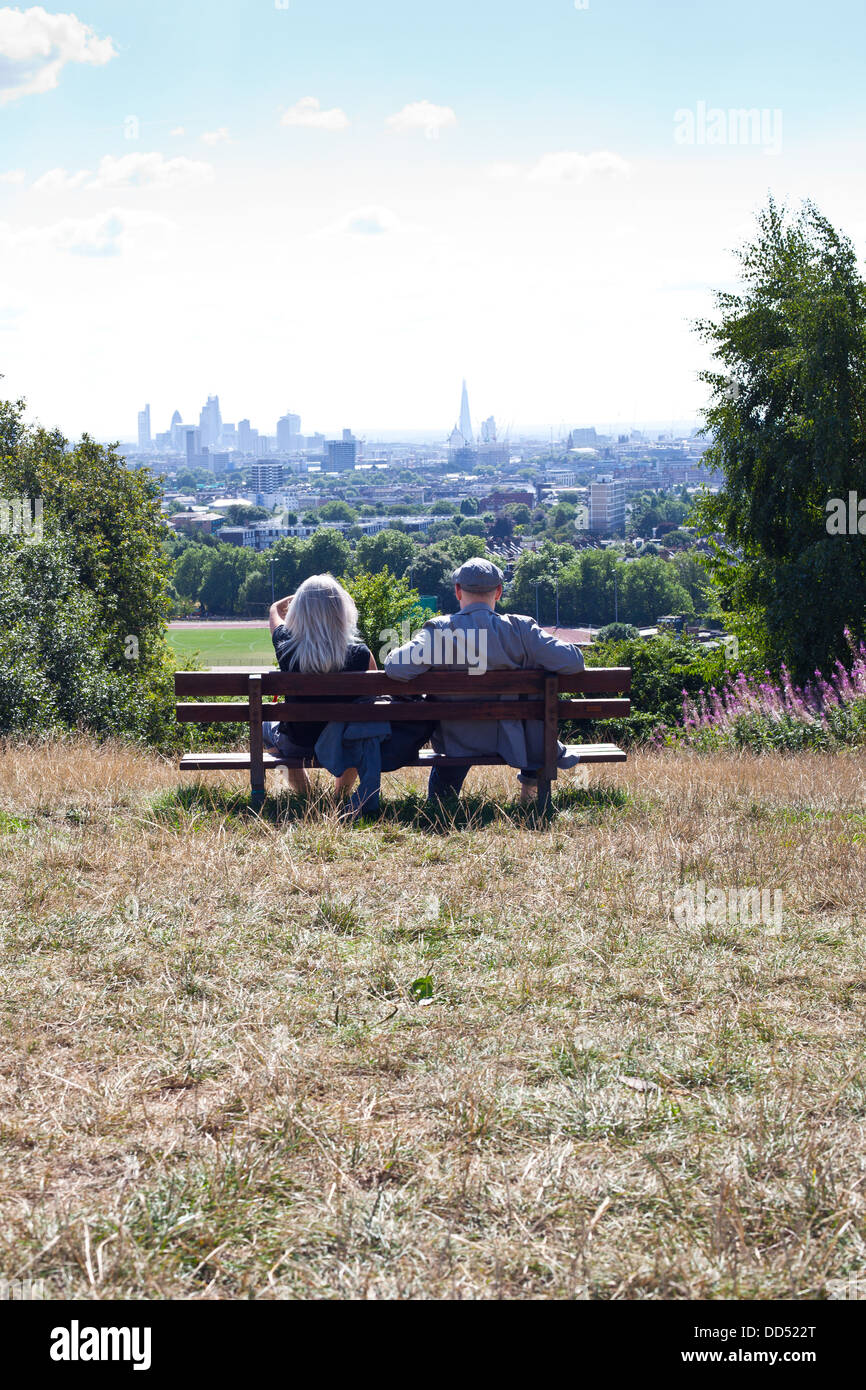 Couple sitting on bench looking at London skyline from Parliament Hill ...