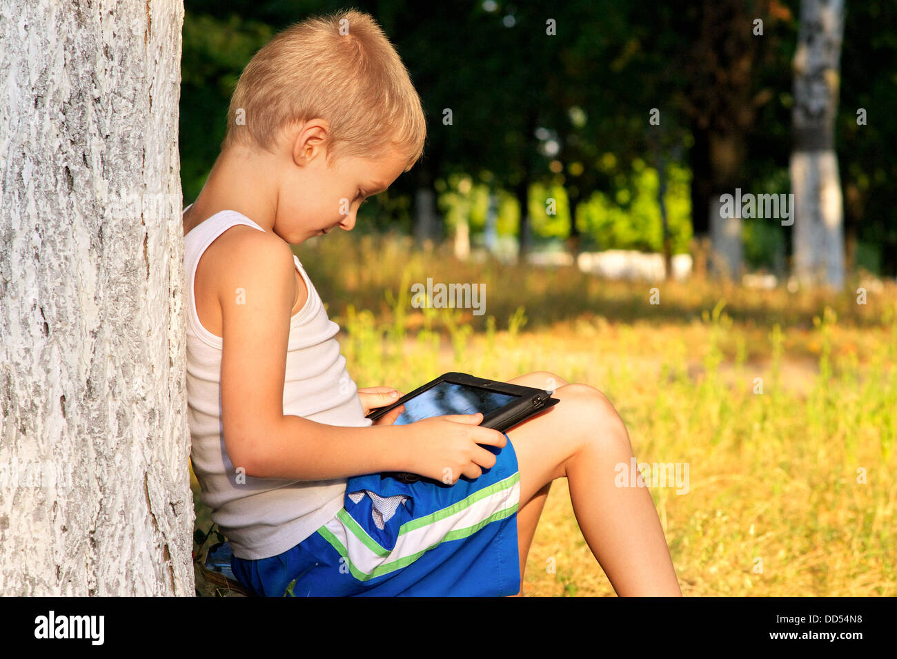 Boy Child playing with Tablet PC Outdoor with forest on background ...