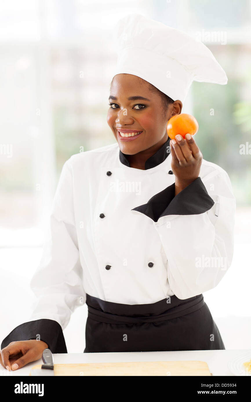 beautiful young female African chef holding fresh tomato Stock Photo ...