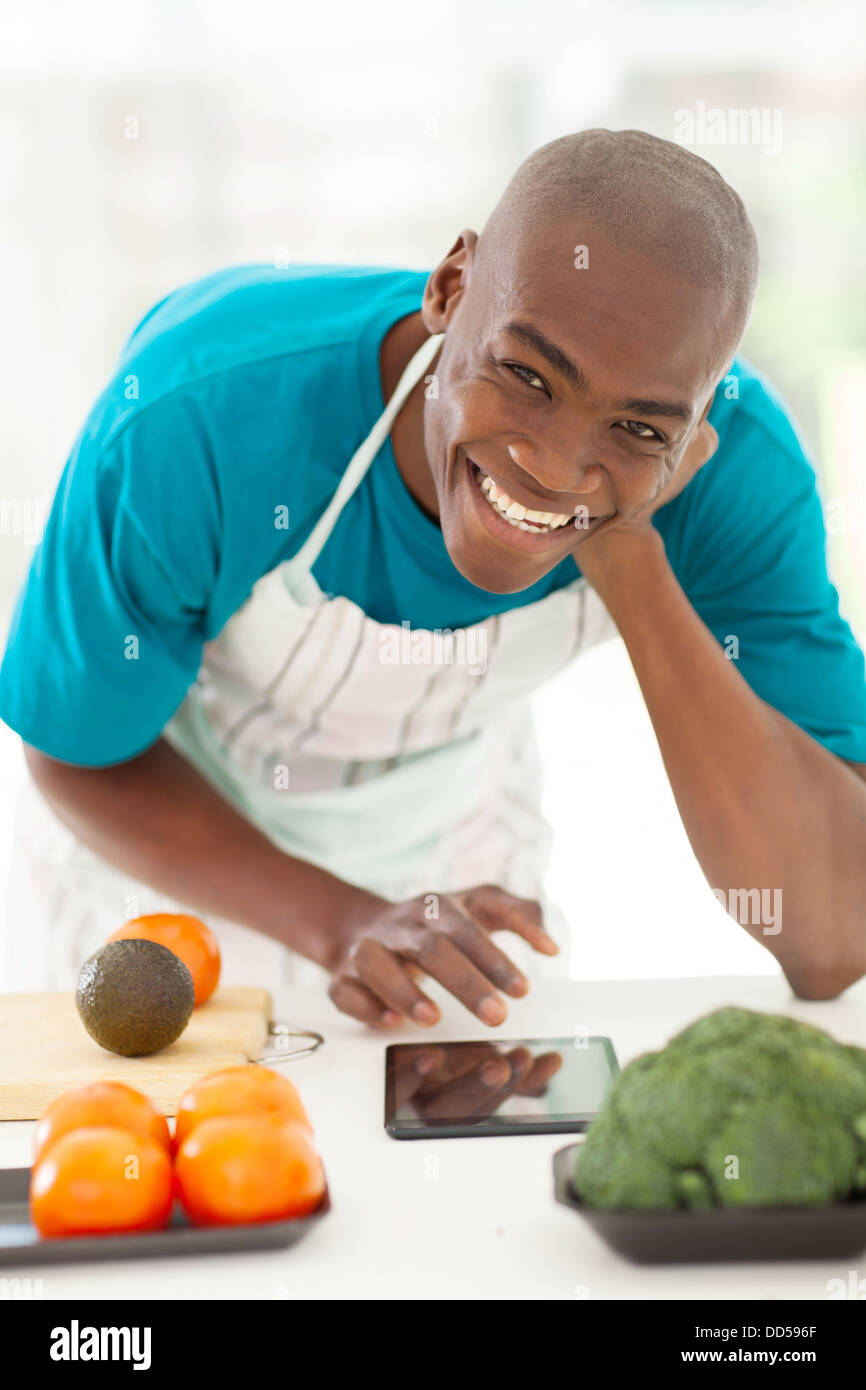 cheerful afro American man in kitchen searching recipe on tablet ...