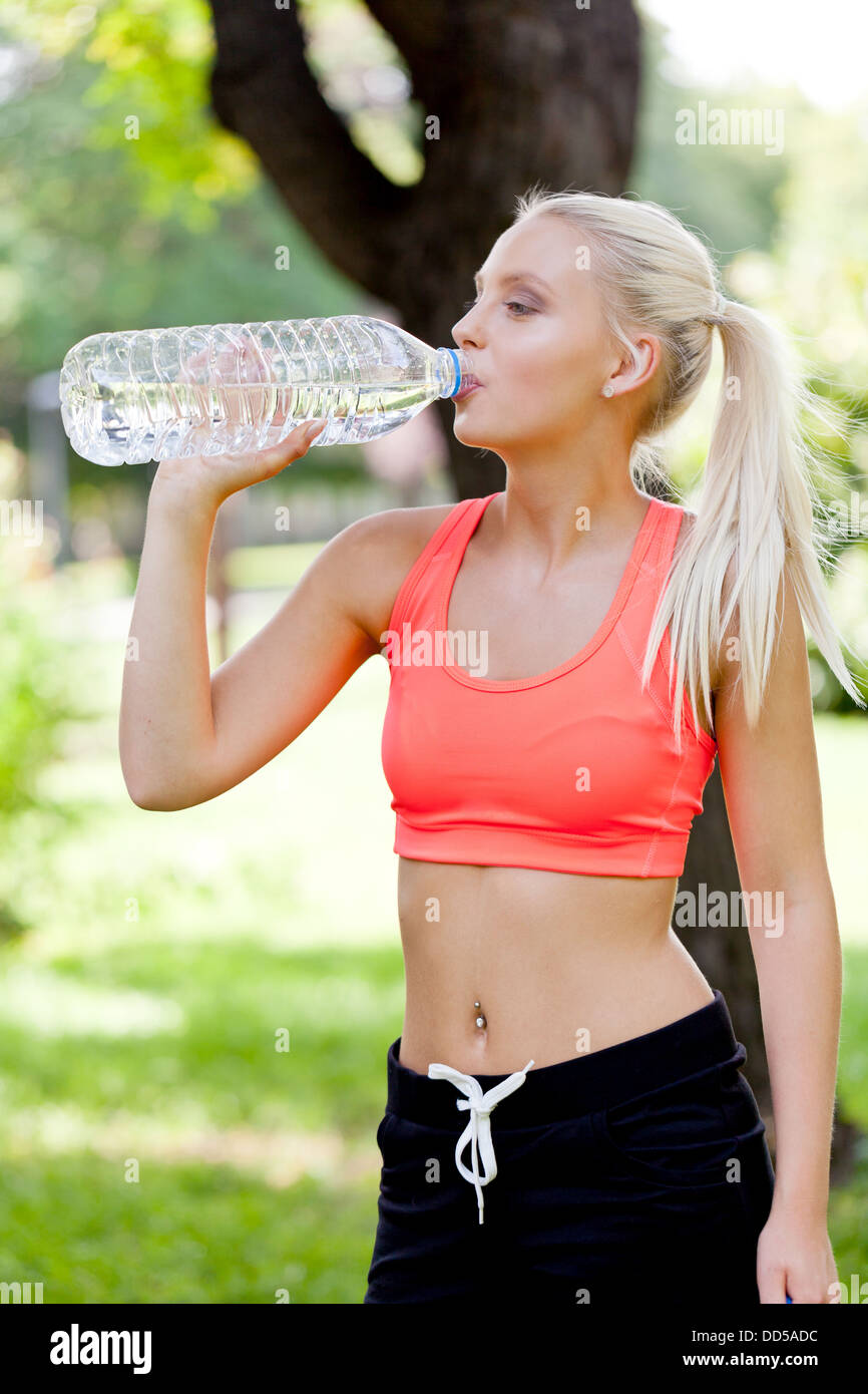 attractive young blonde woman drinking water outdoor sport in summer ...