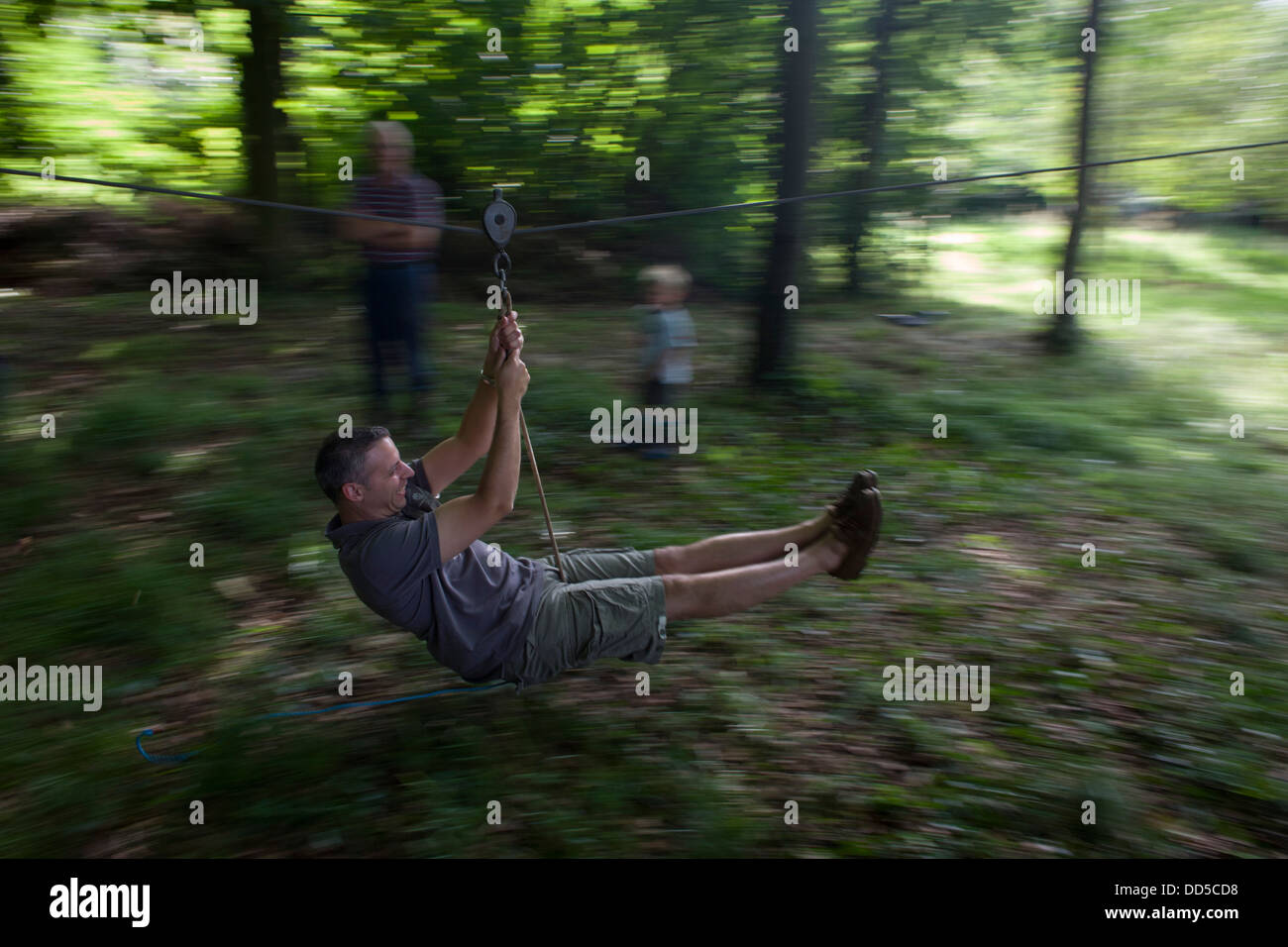 A 40 year-old man blurs across woodland during a home-made zip wire ...