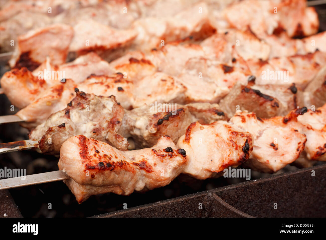 Shish kebab in process of cooking on open fire outdoors / Juicy slices ...