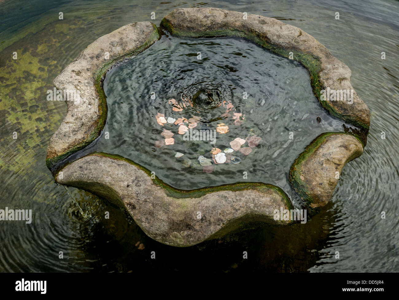 A stone wishing well with coins in the water Stock Photo - Alamy