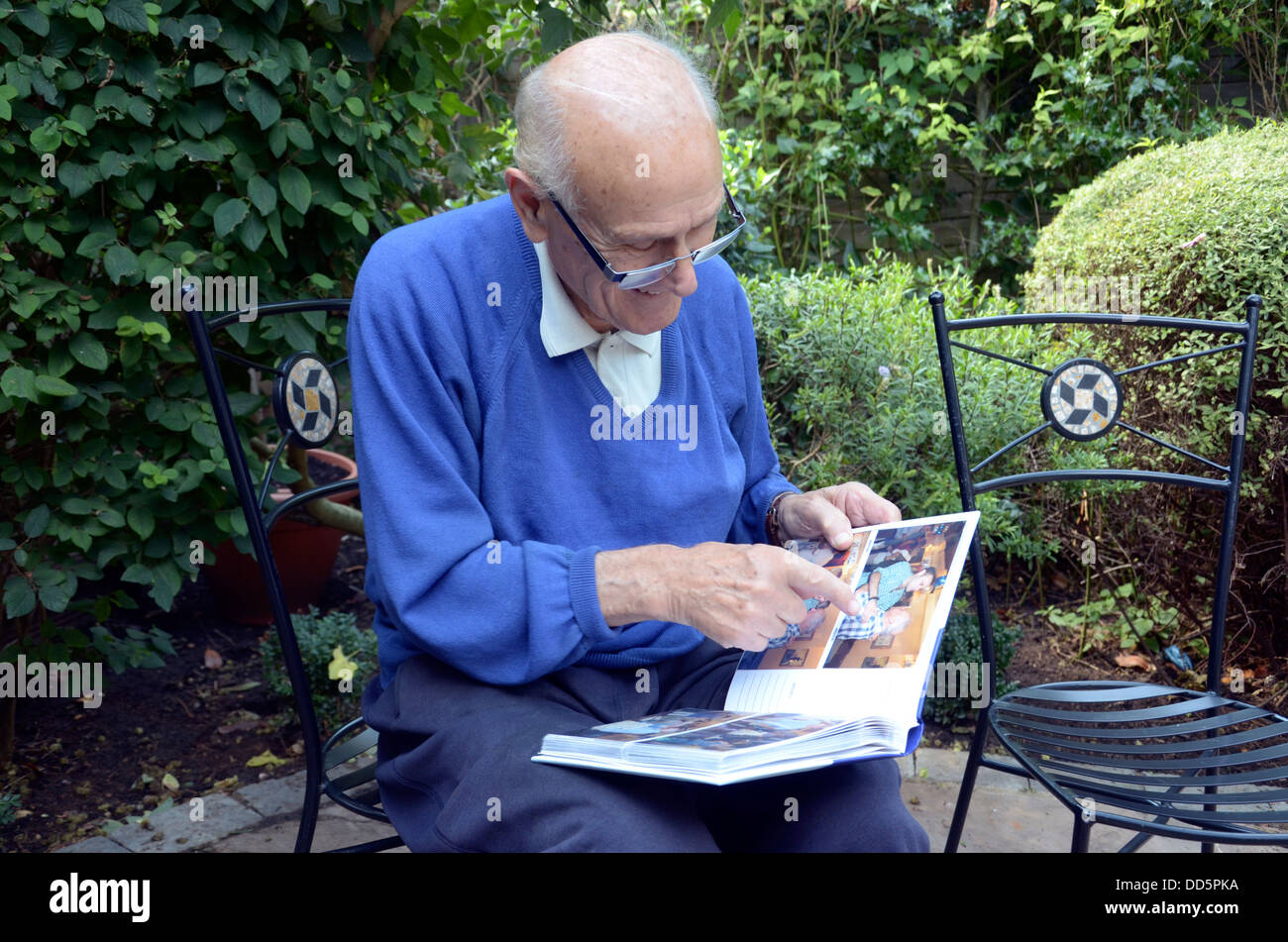 An elderly man looking through a photo album and reminiscing and ...