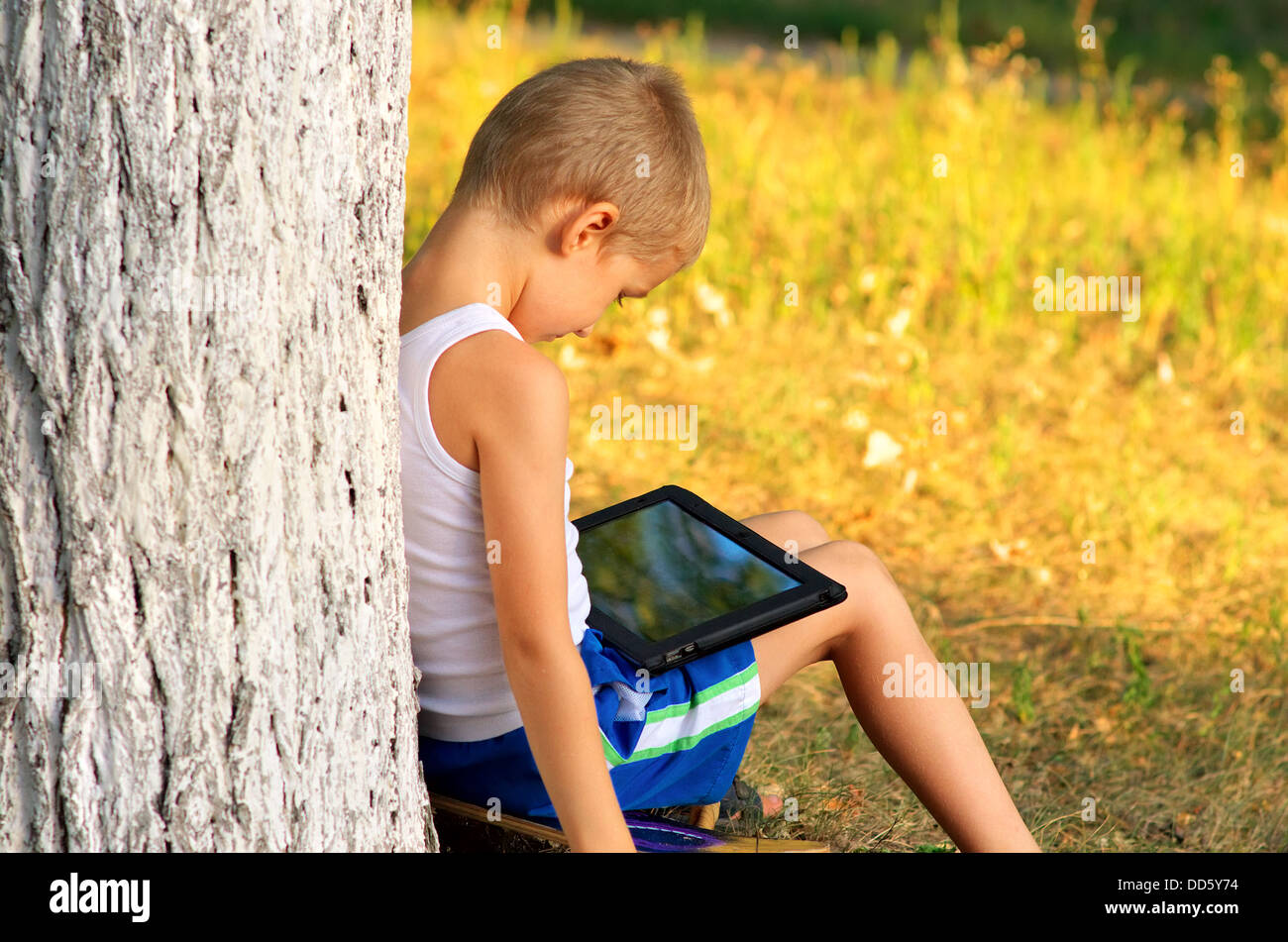 Boy Child playing with Tablet PC Outdoor with forest on background ...