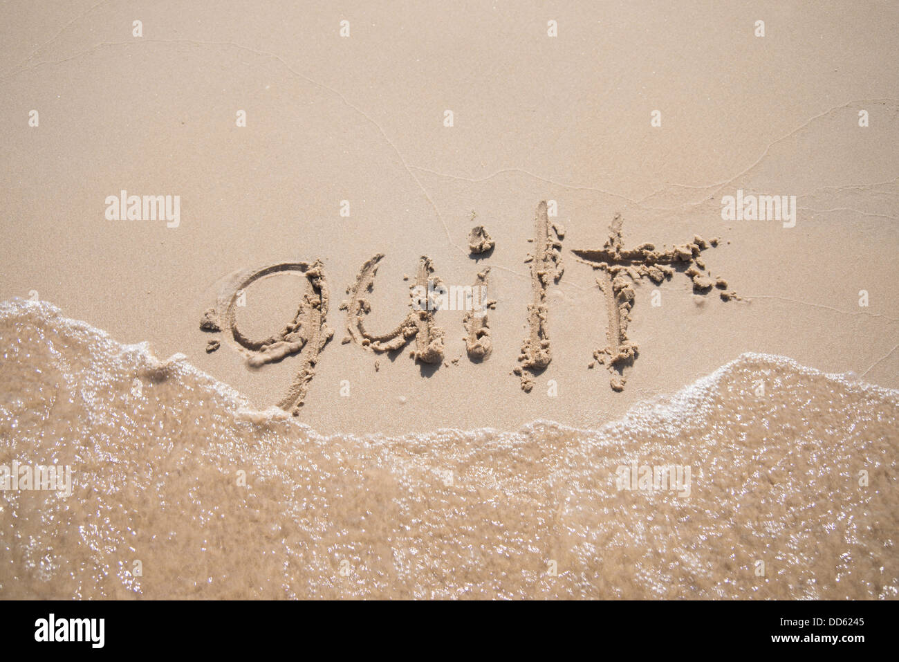 The word "guilt" written in the sand, being washed away by a wave Stock ...