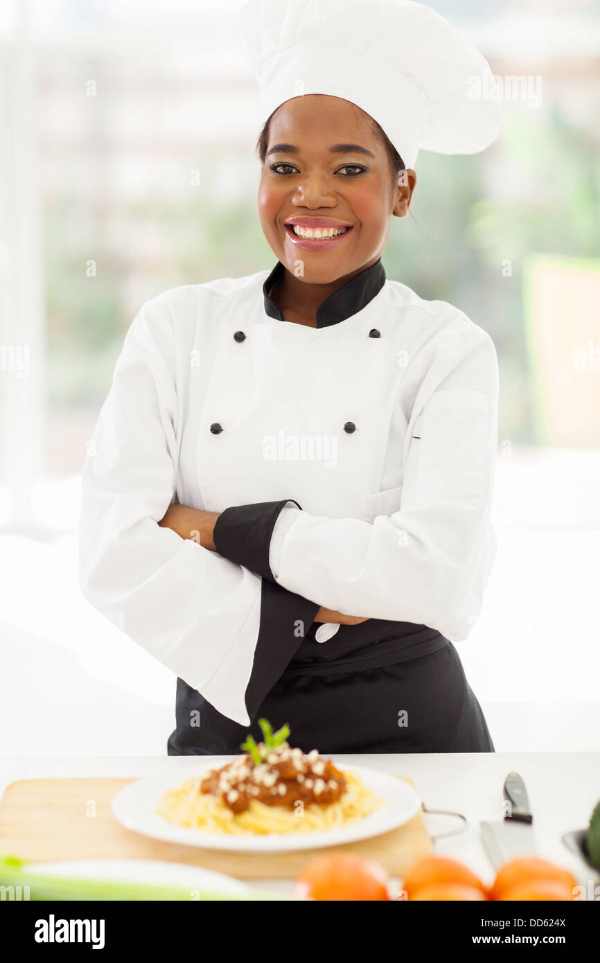 pretty female African chef with arms crossed standing in hotel kitchen ...