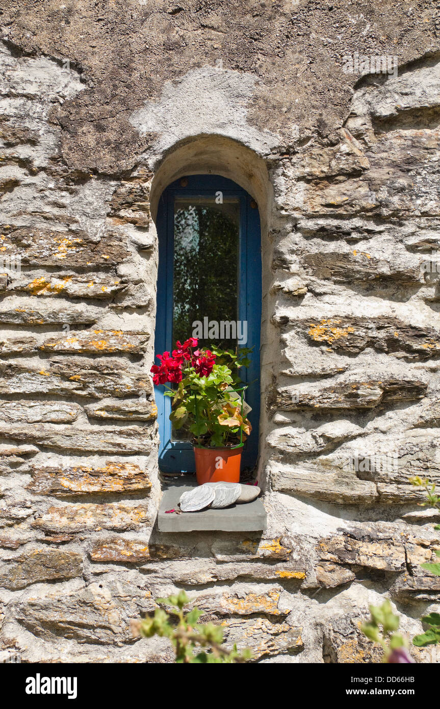 Vertical close up of a small arched window in an old stone cottage ...