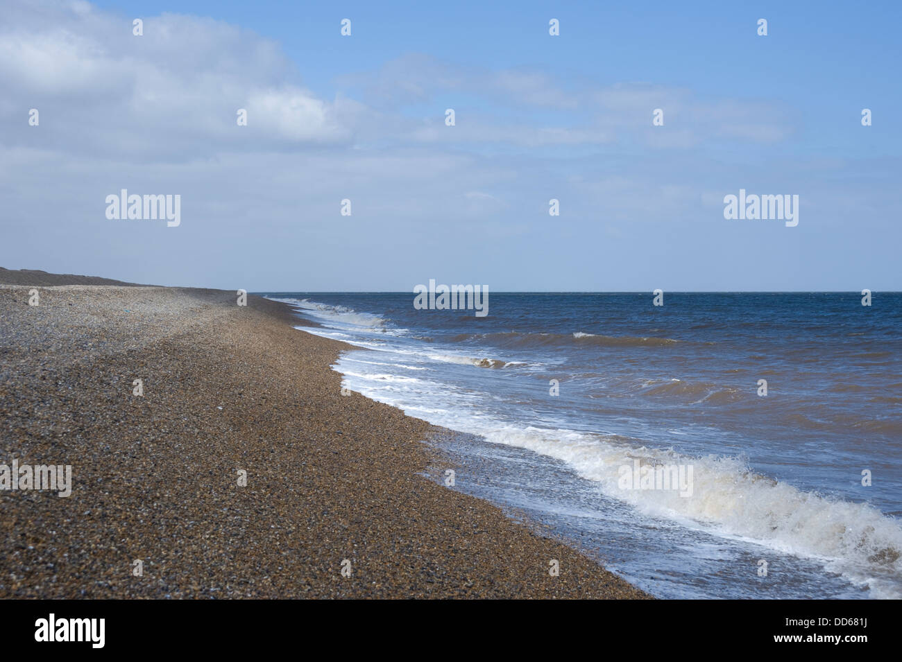 Shingle beach and sea defenses with waves lapping the shore at Cley ...