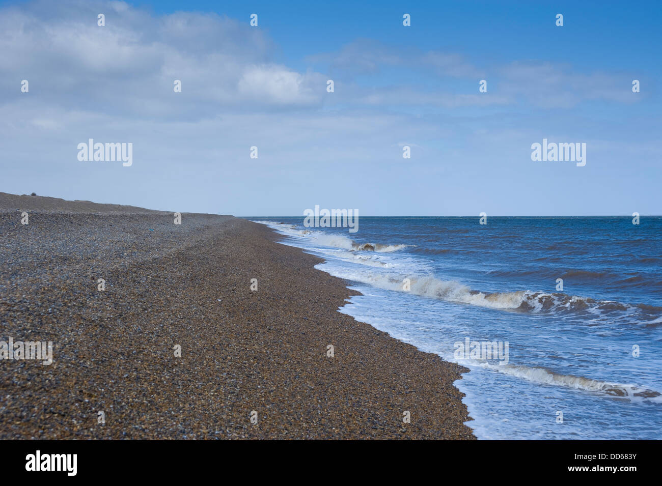 Shingle beach and sea defenses with waves lapping the shore at Cley ...