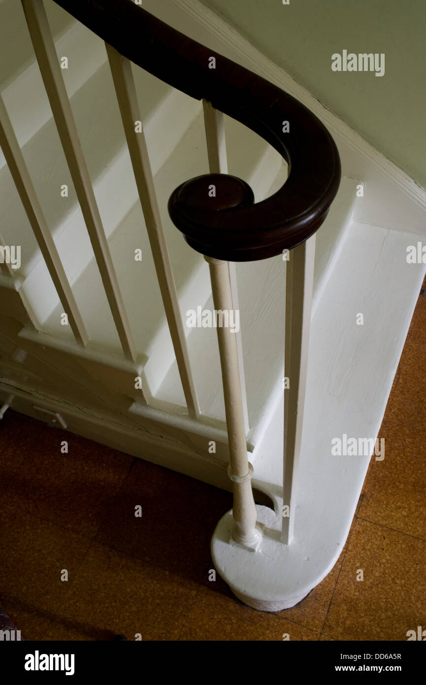 View of the bottom of a flight of house stairs with a curved banister ...