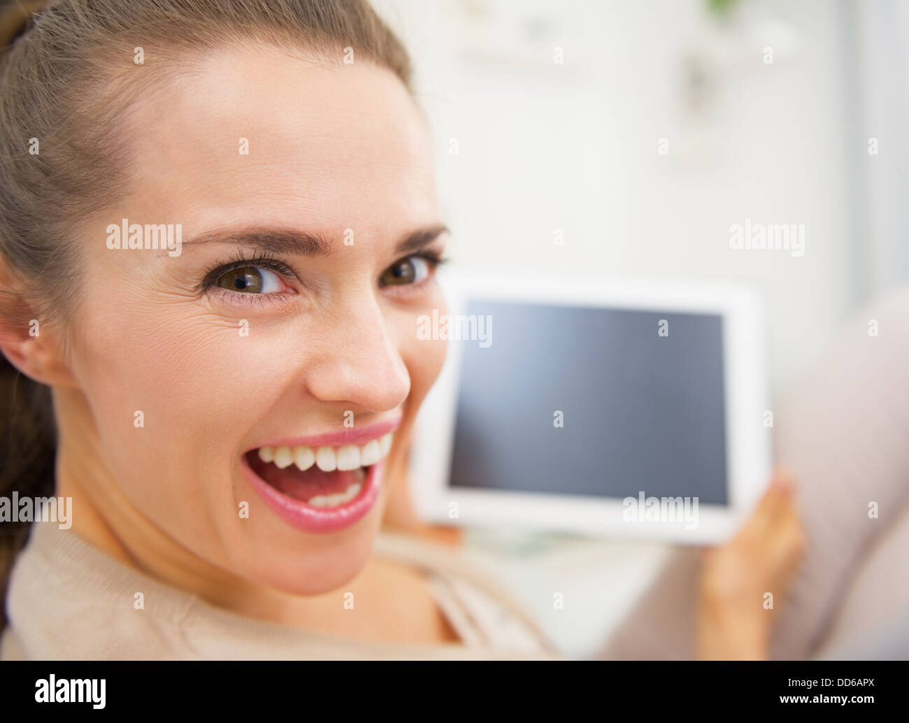 Funny Portrait Of Smiling Young Woman Sitting On Divan And Using Tablet