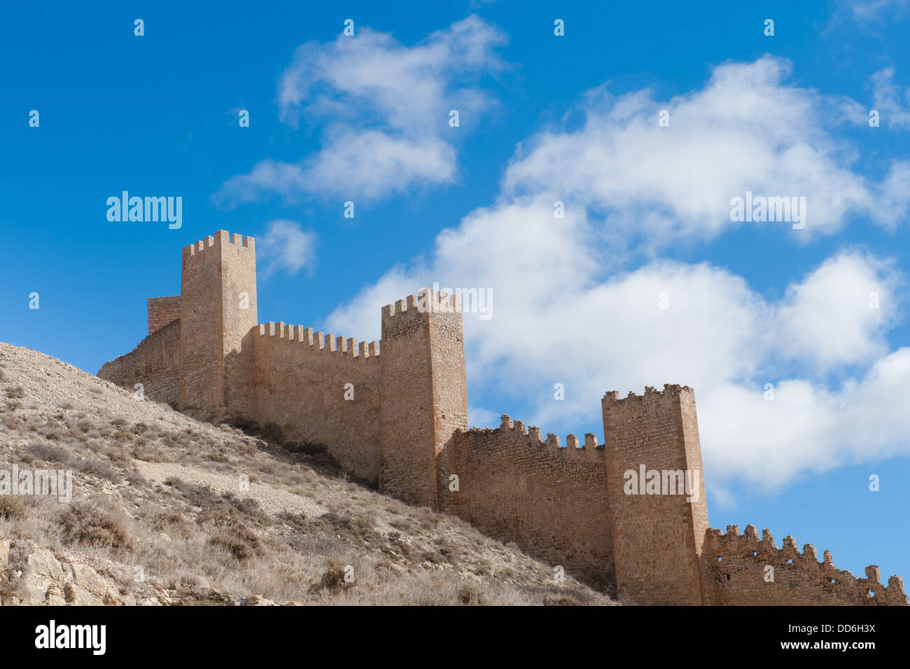 Spanish medieval stone city walls on the hill against a blue sky ...