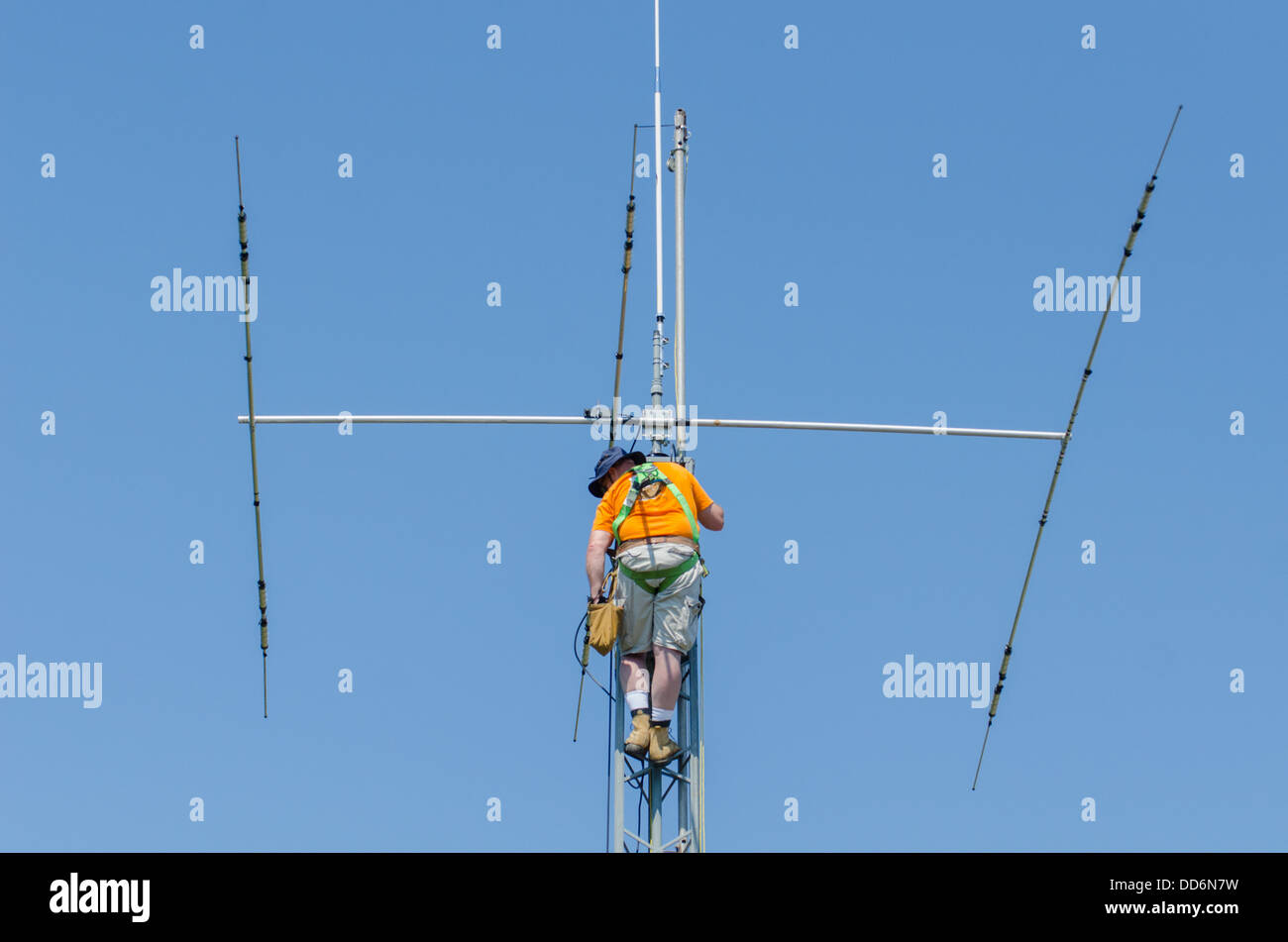 Man in safety harness installing an amateur radio tower and antenna ...