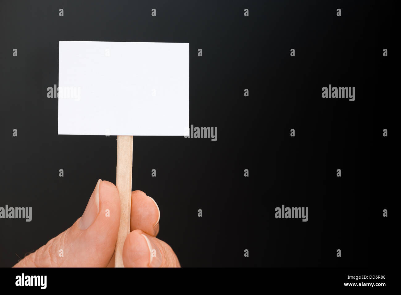 Hand Holding Tiny Sign on Black with Copy Space Stock Photo - Alamy