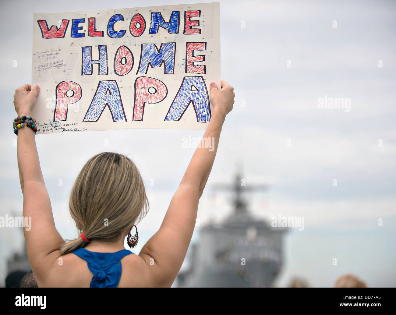A young woman holds a sign welcoming home her father as the US Navy ...