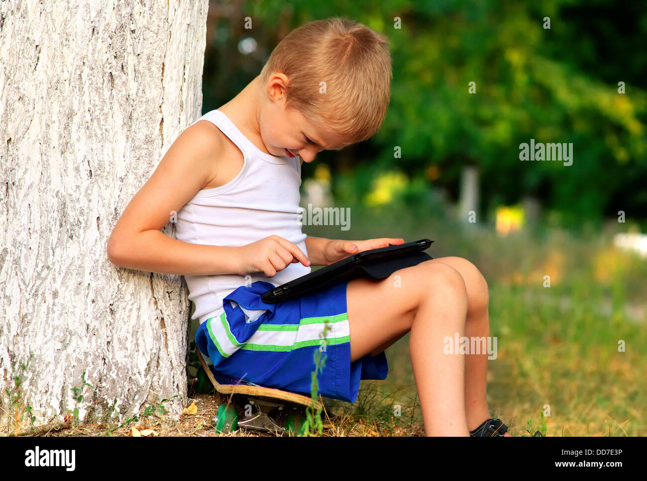 Boy Child playing with Tablet PC Outdoor with forest on background ...