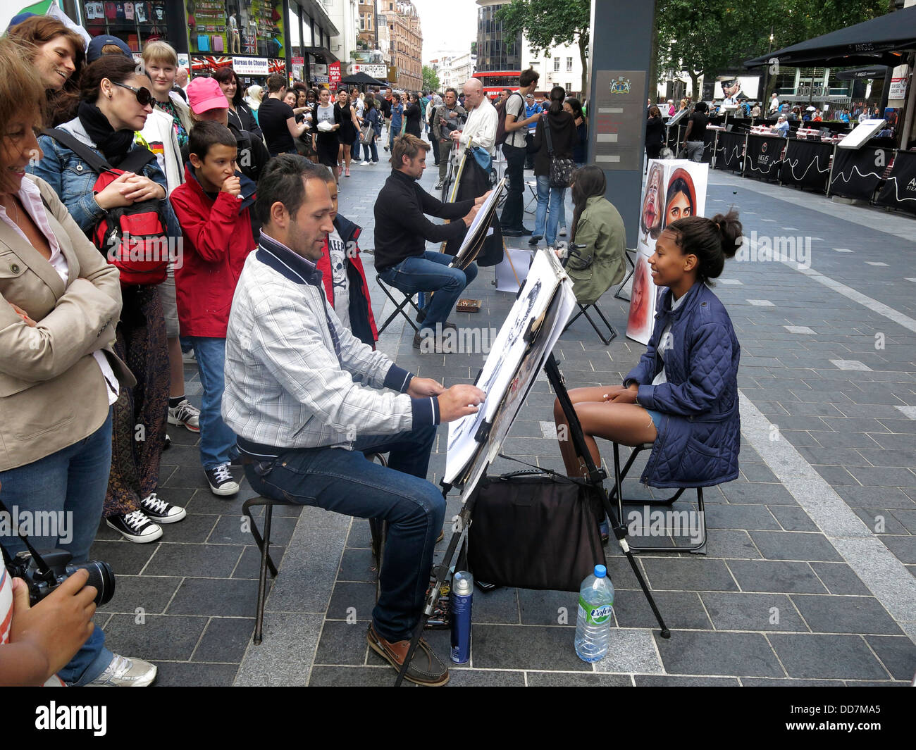 A crowd of people watch a portrait artist at work sketching a woman ...