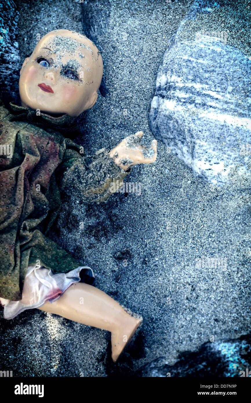a broken doll, half buried in sand Stock Photo - Alamy