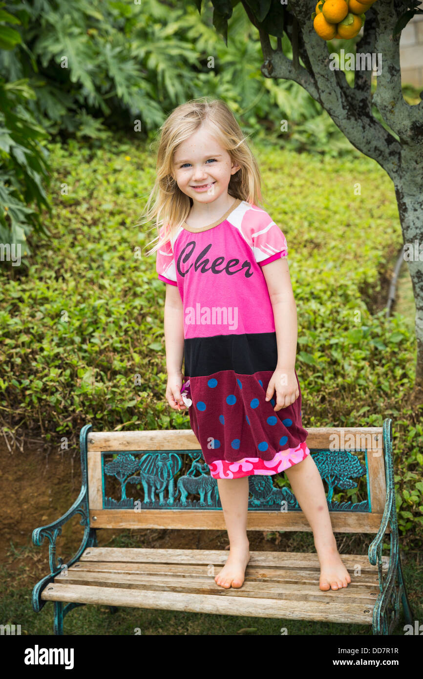 Smiling girl standing on park bench Stock Photo - Alamy