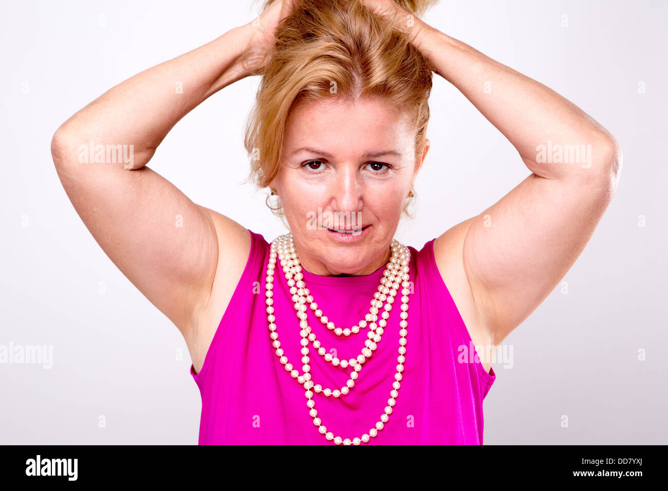 Mature Blonde Lady with Both Arms up holding her hair, she has pearl ...