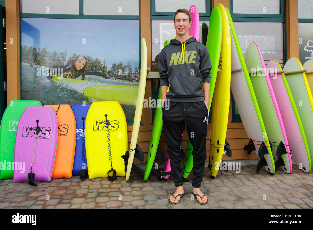Laid back Teenage boy standing in front of surfboards at surf shop ...