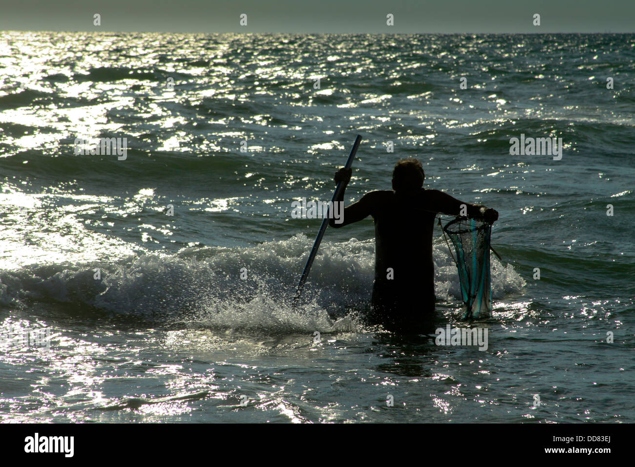 Fisherman in the sea at sunset Stock Photo - Alamy