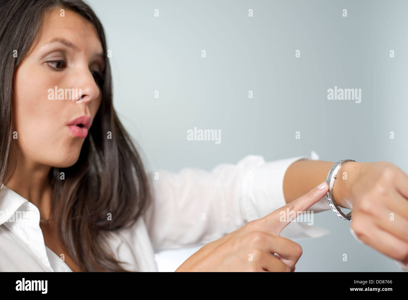 Irritated businesswoman tapping her watch and frowning as she is kept ...