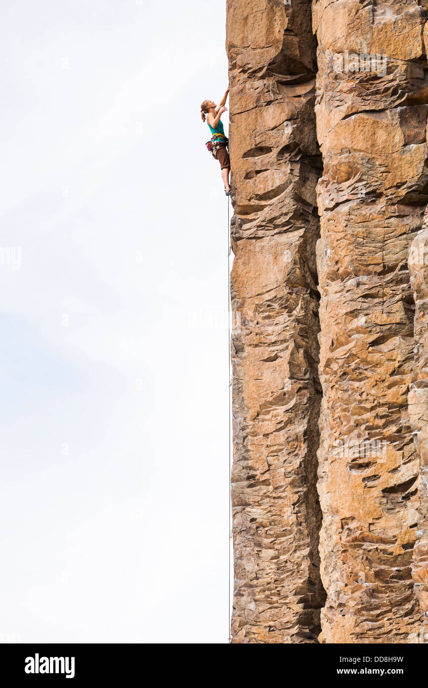 A woman climbing a basalt rock cliff in central Washington State, USA ...
