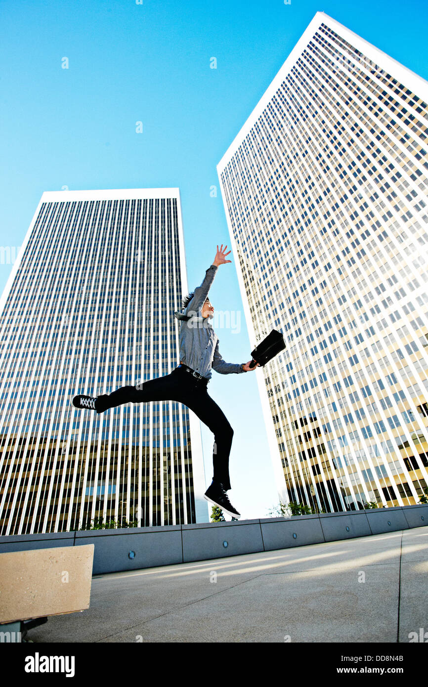 Asian businessman leaping on urban rooftop Stock Photo - Alamy