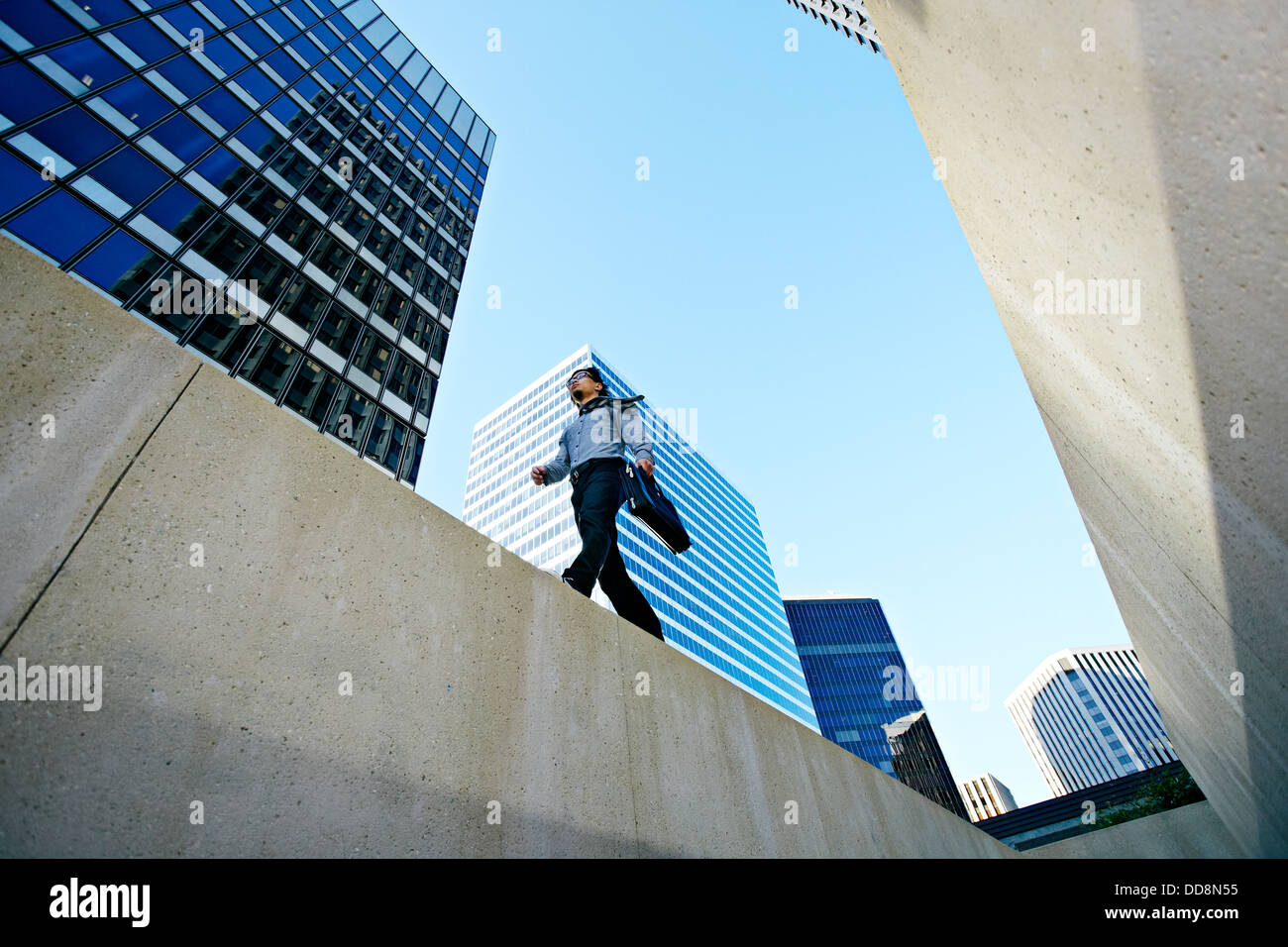 Asian businessman walking on ledge in city Stock Photo - Alamy