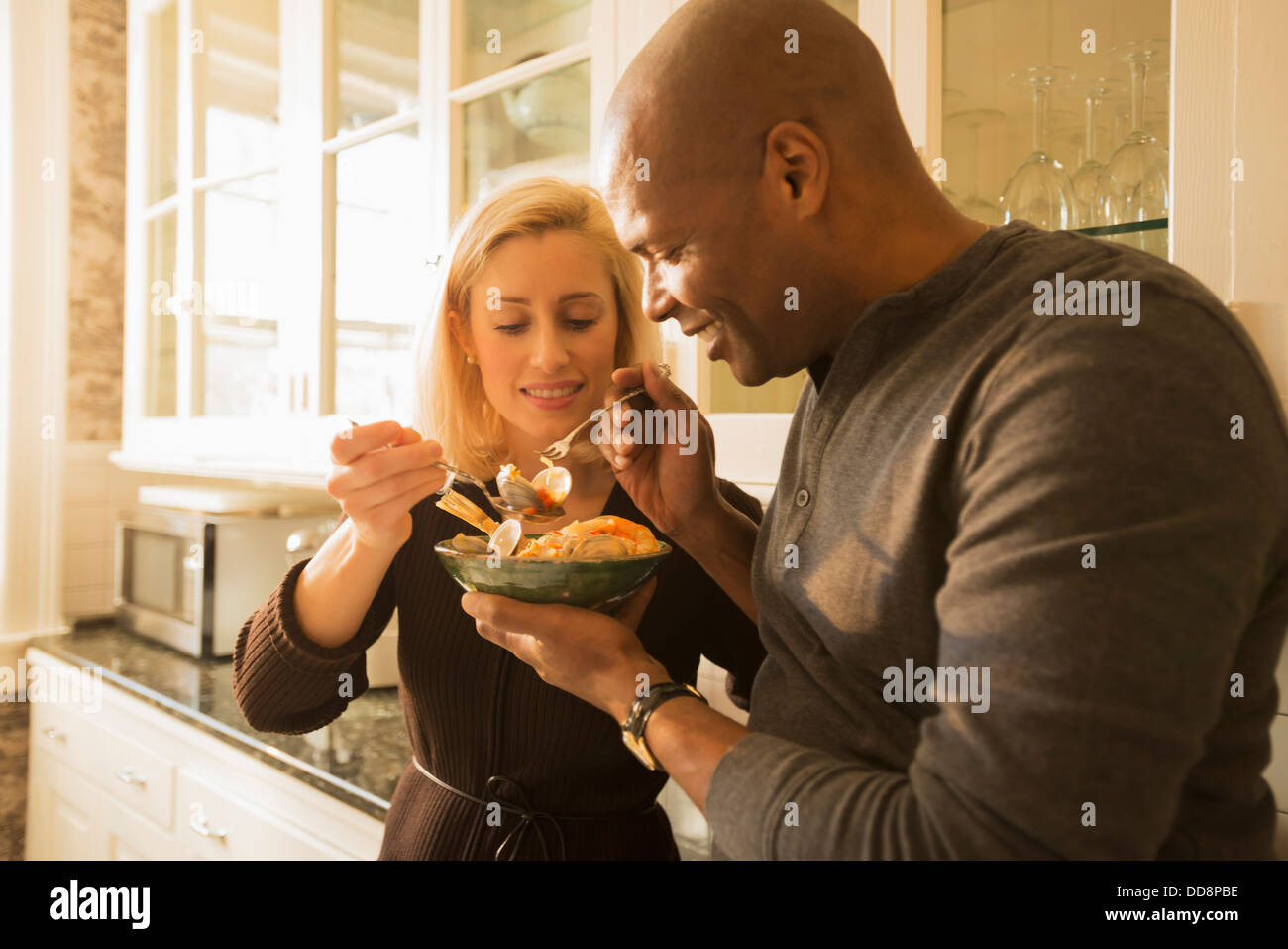 Couple sharing bowl of seafood stew in kitchen Stock Photo - Alamy